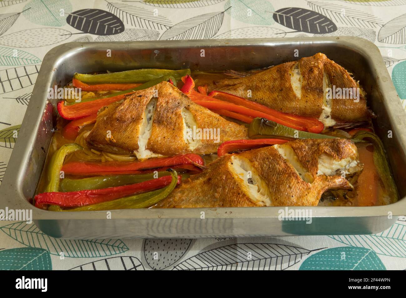 Homemade roasted red fish with red, green peppers and onions ready to ...