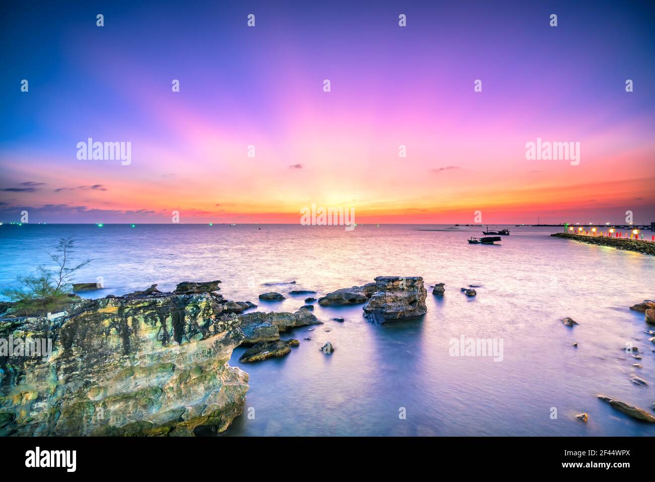 Sunset on the bay colorful sky, below is a large rock formation towards ...