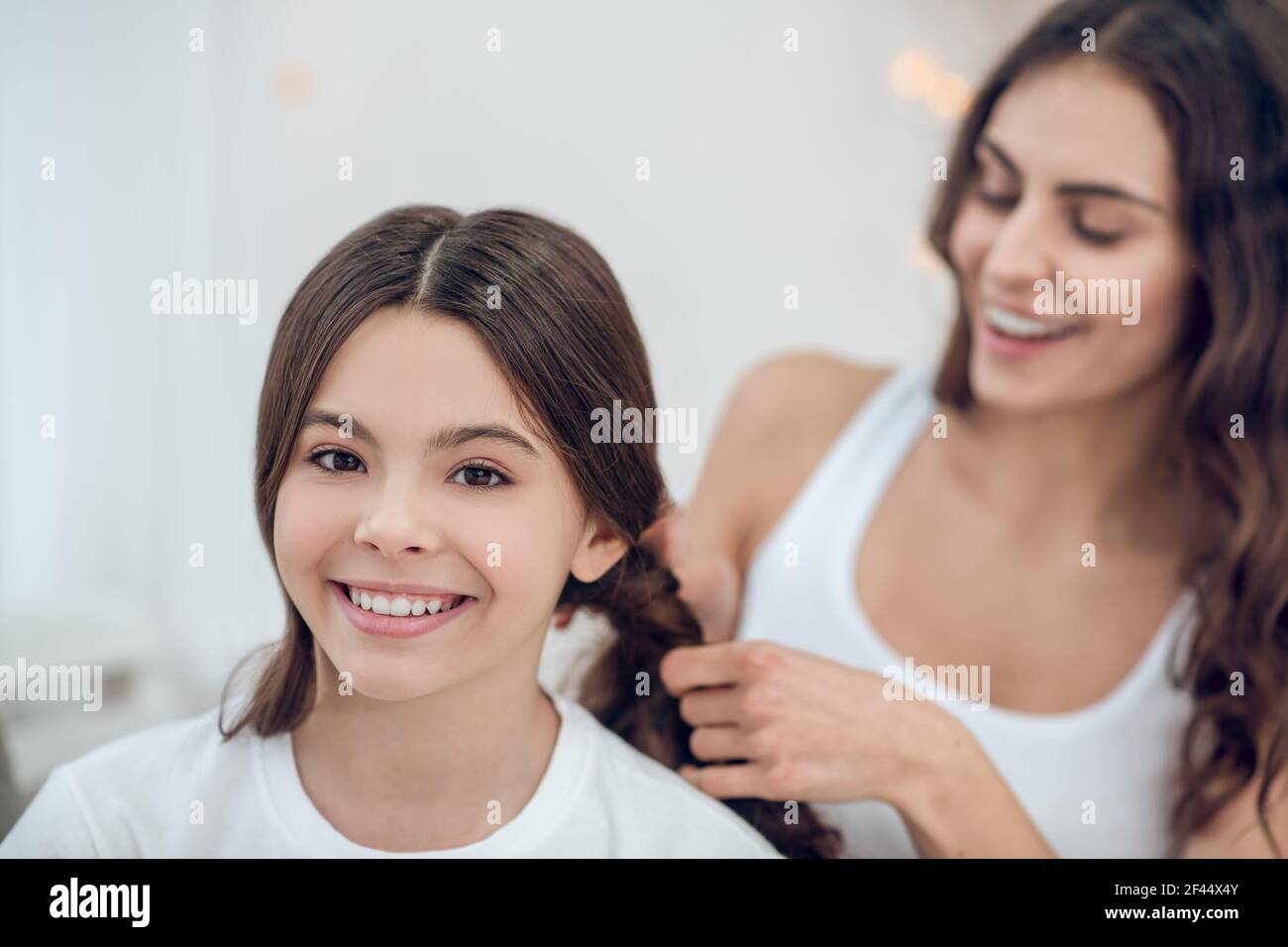 Mom braiding her happy daughters braids Stock Photo - Alamy