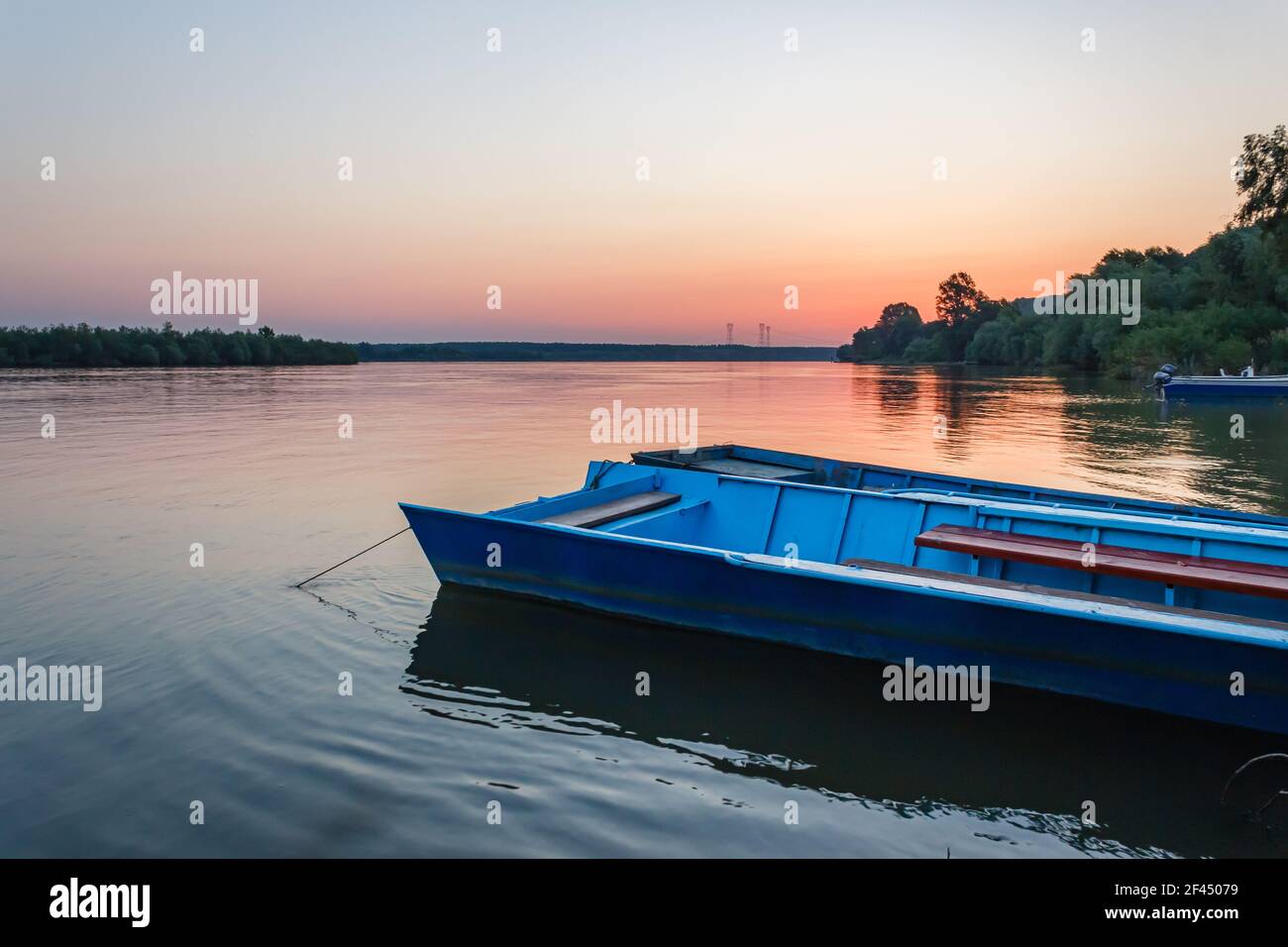 The scenic sunset over the Danube river with parked boats in Serbia ...