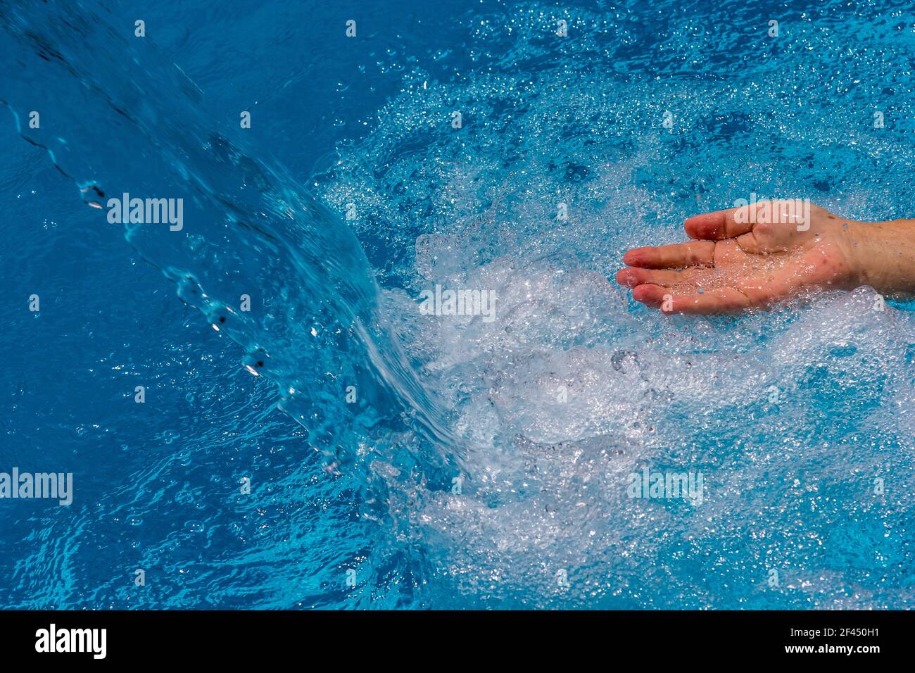 The hand of a person in the crystal blue water of a pool Stock Photo ...