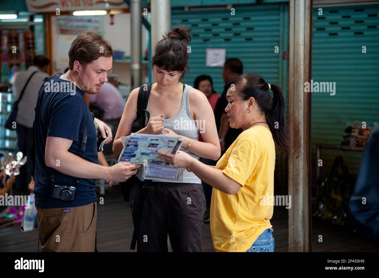 Western tourists asking a local for directions using a map at a boat ...