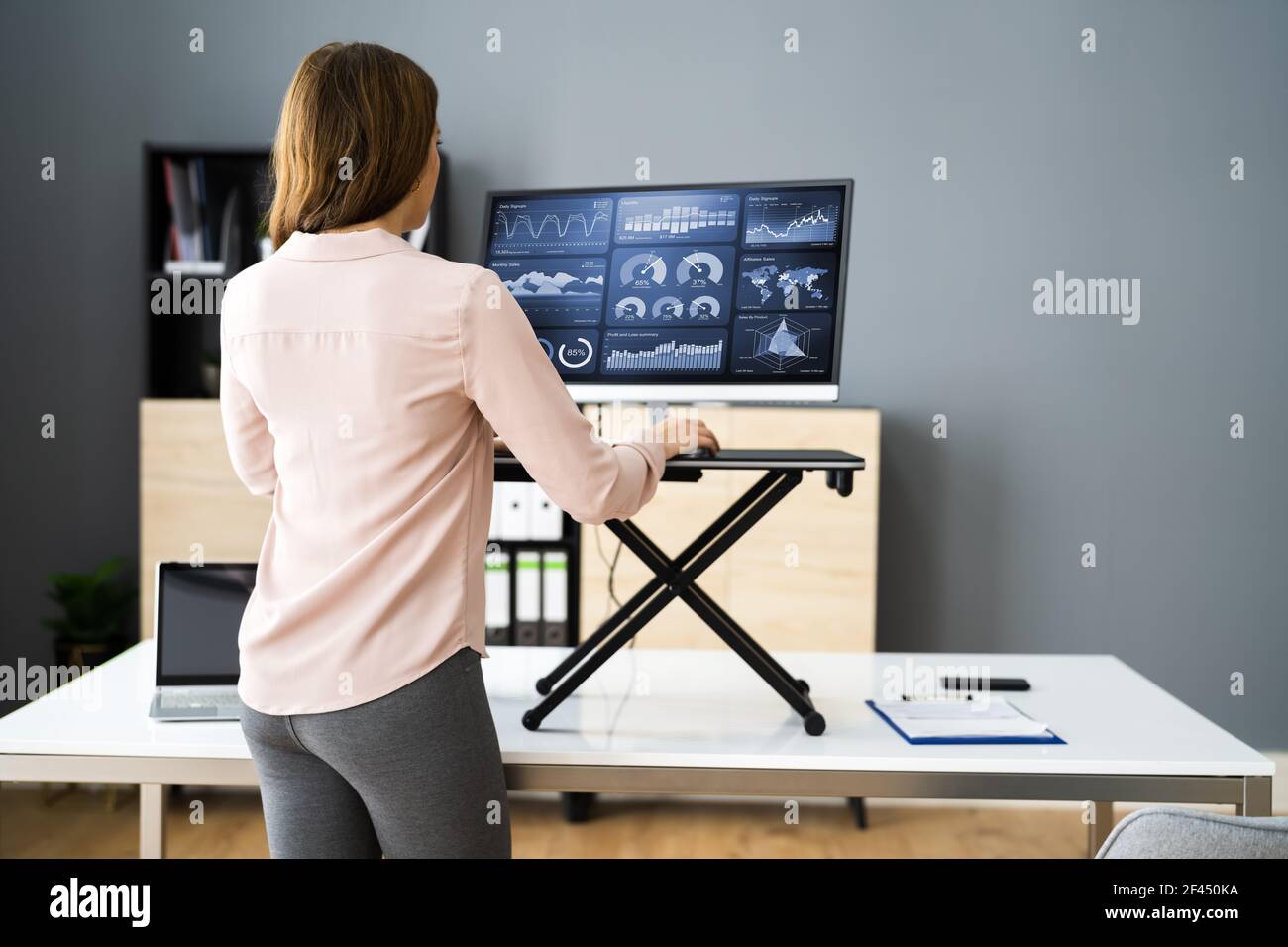 Adjustable Height Desk Stand In Office Using Computer Stock Photo - Alamy