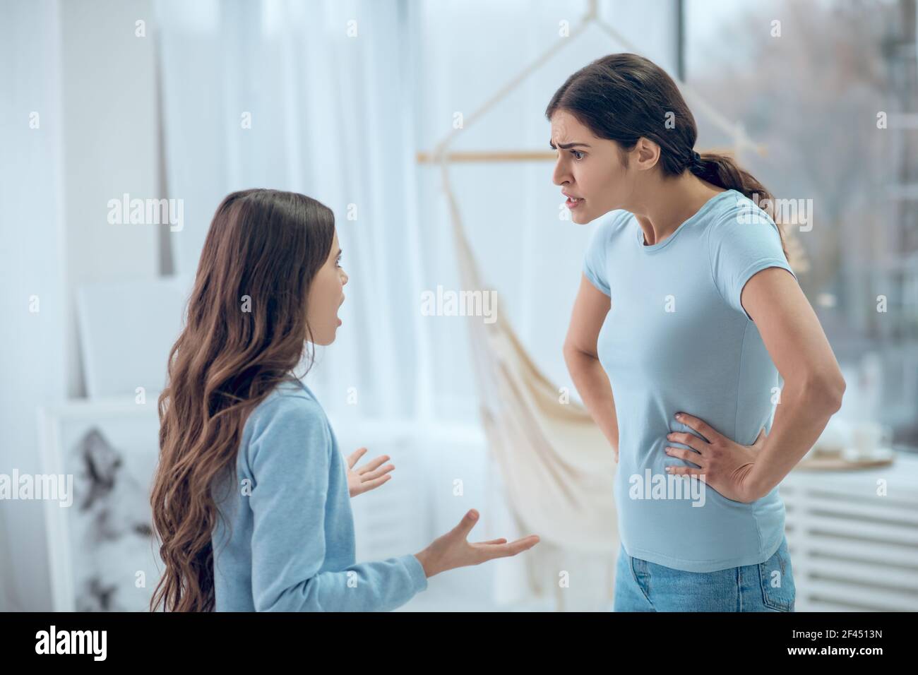 Shocked indignant mom standing in front of stubborn daughter Stock ...