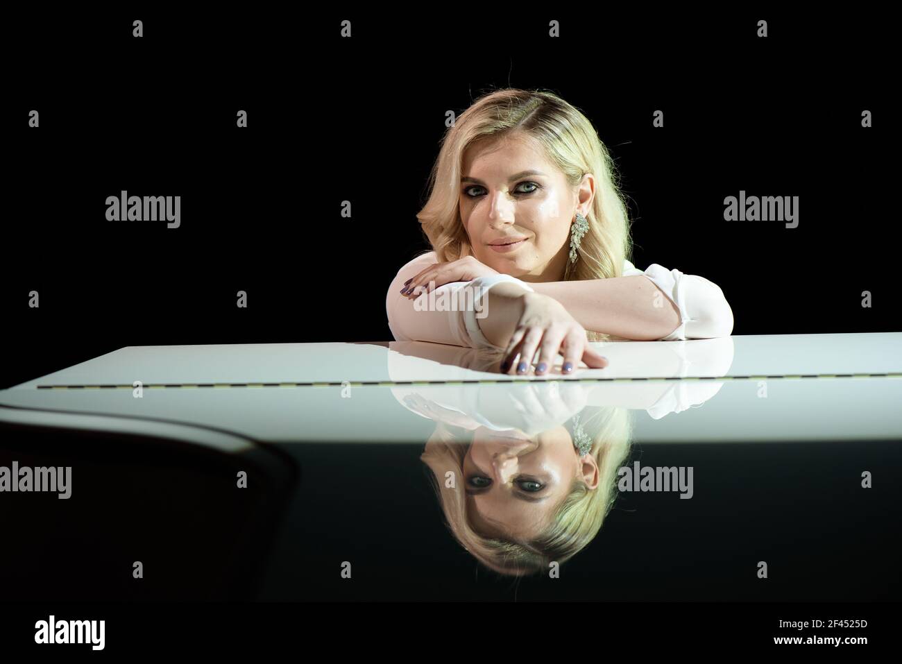 Portret of pianist posing near white piano on the stage in the beam of ...