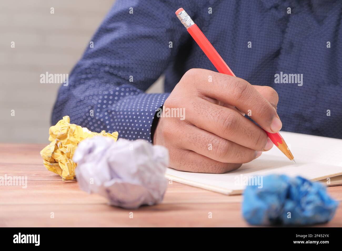 crumpled paper ball and person writing on notepad on wooden table Stock ...