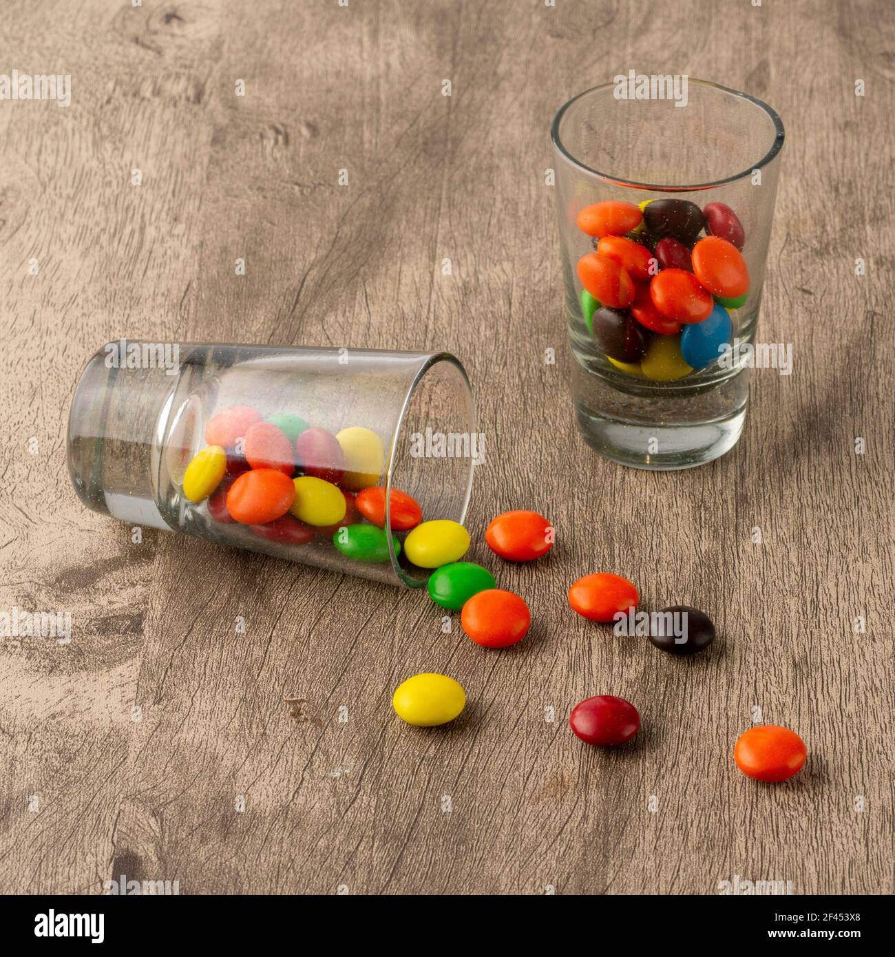 Colorful candies on glasses and spread over wooden table Stock Photo ...