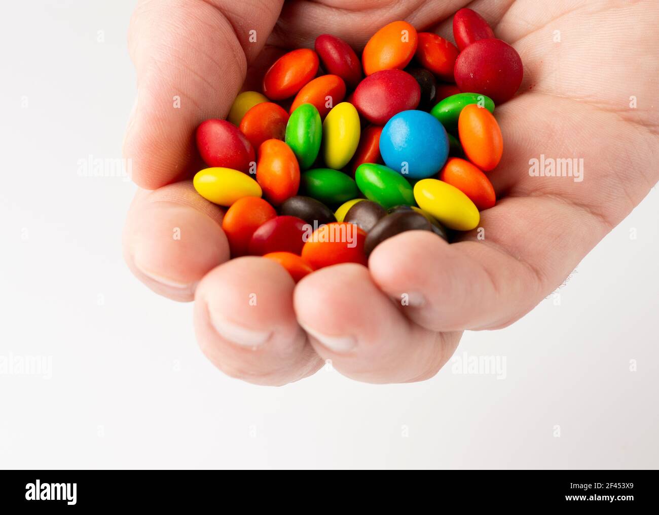Hand holding colorful candies over white background Stock Photo - Alamy