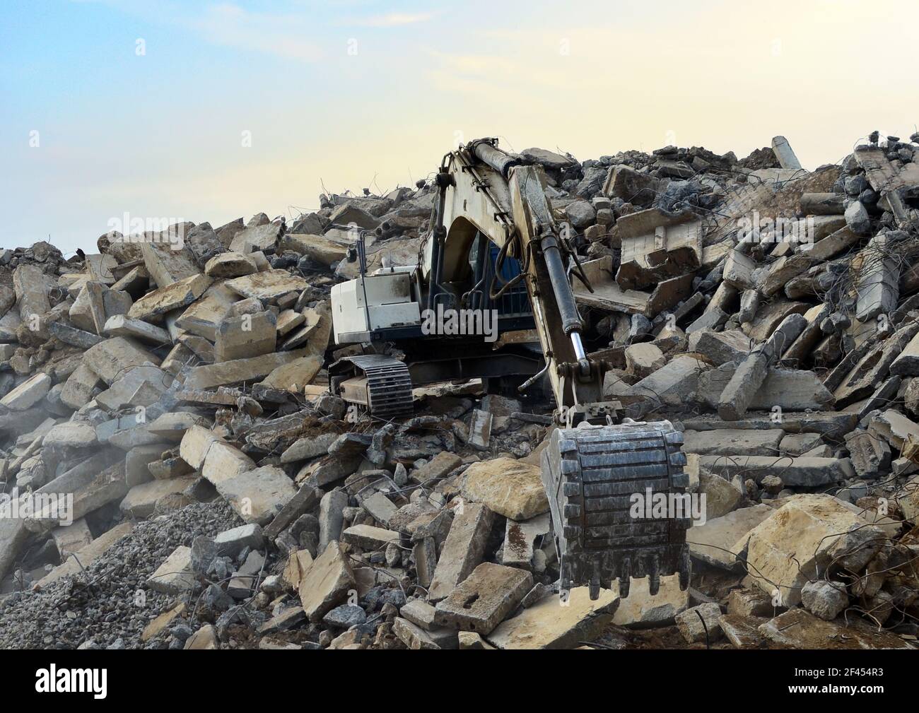 Recycling concrete and construction waste from demolition. Excavator at ...