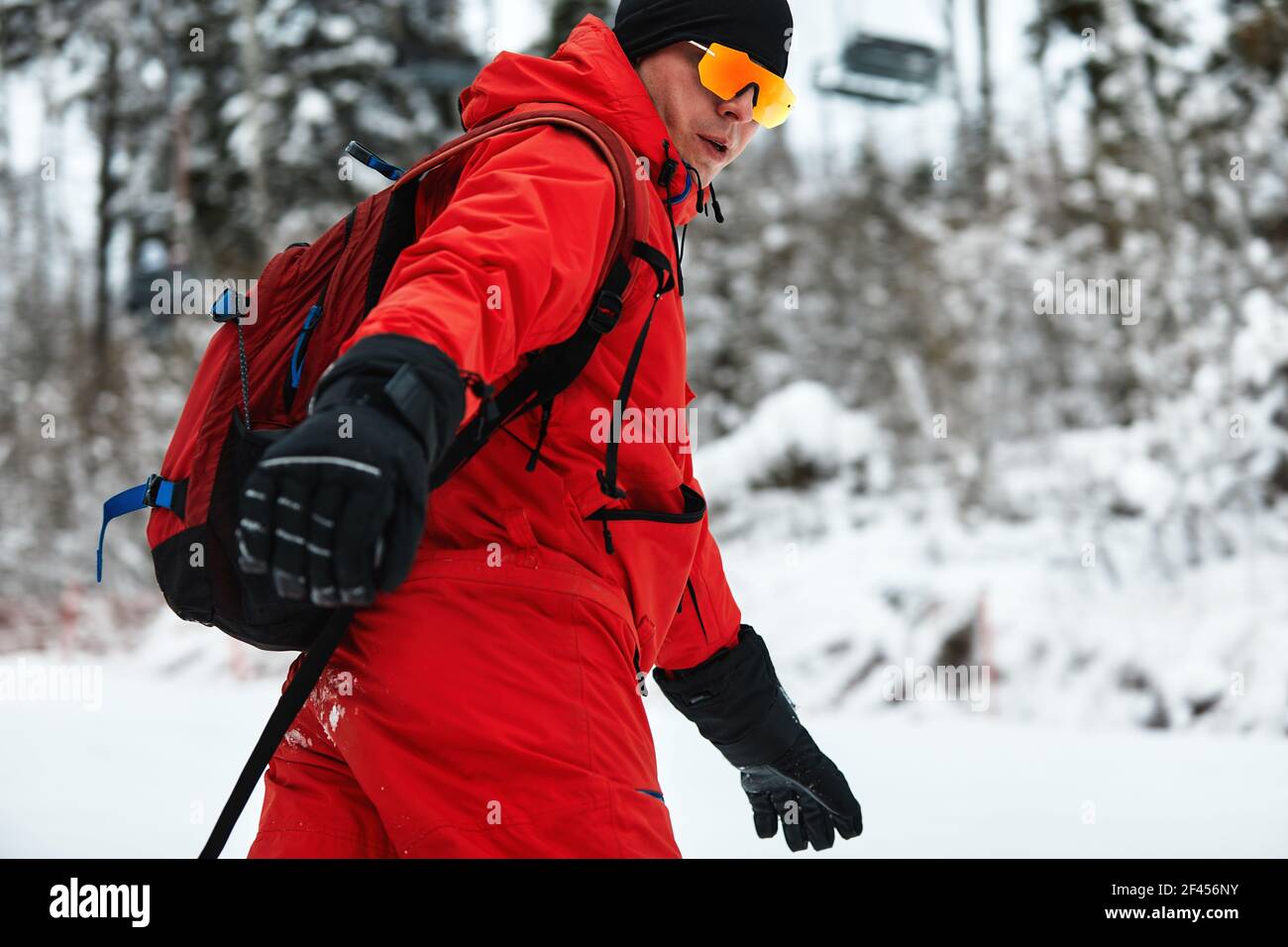 Male snowboarder in a red suit rides on the snowy hill with snowboard ...