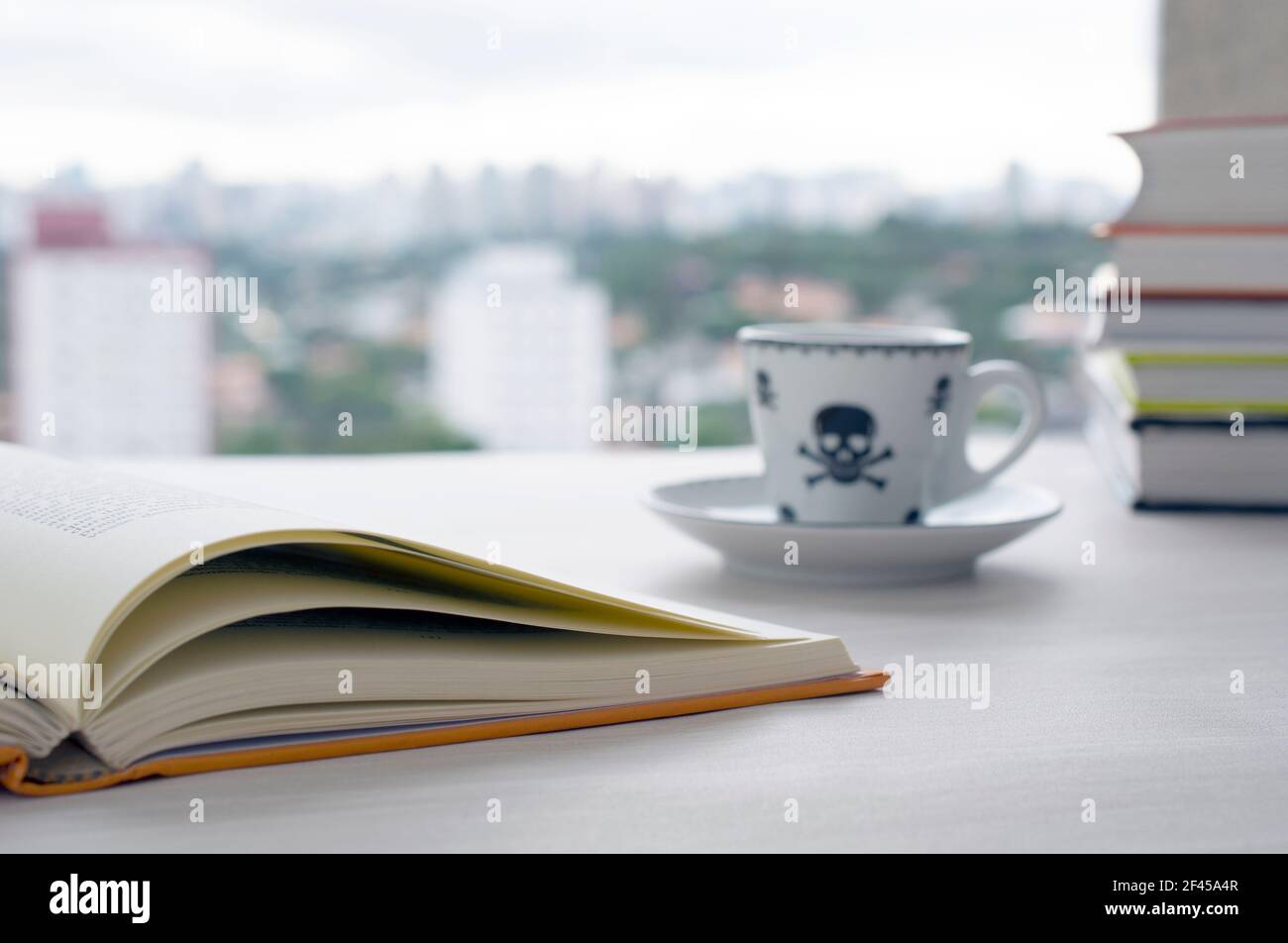 Open book, coffee cup and pile of books over wood table with cityscape ...