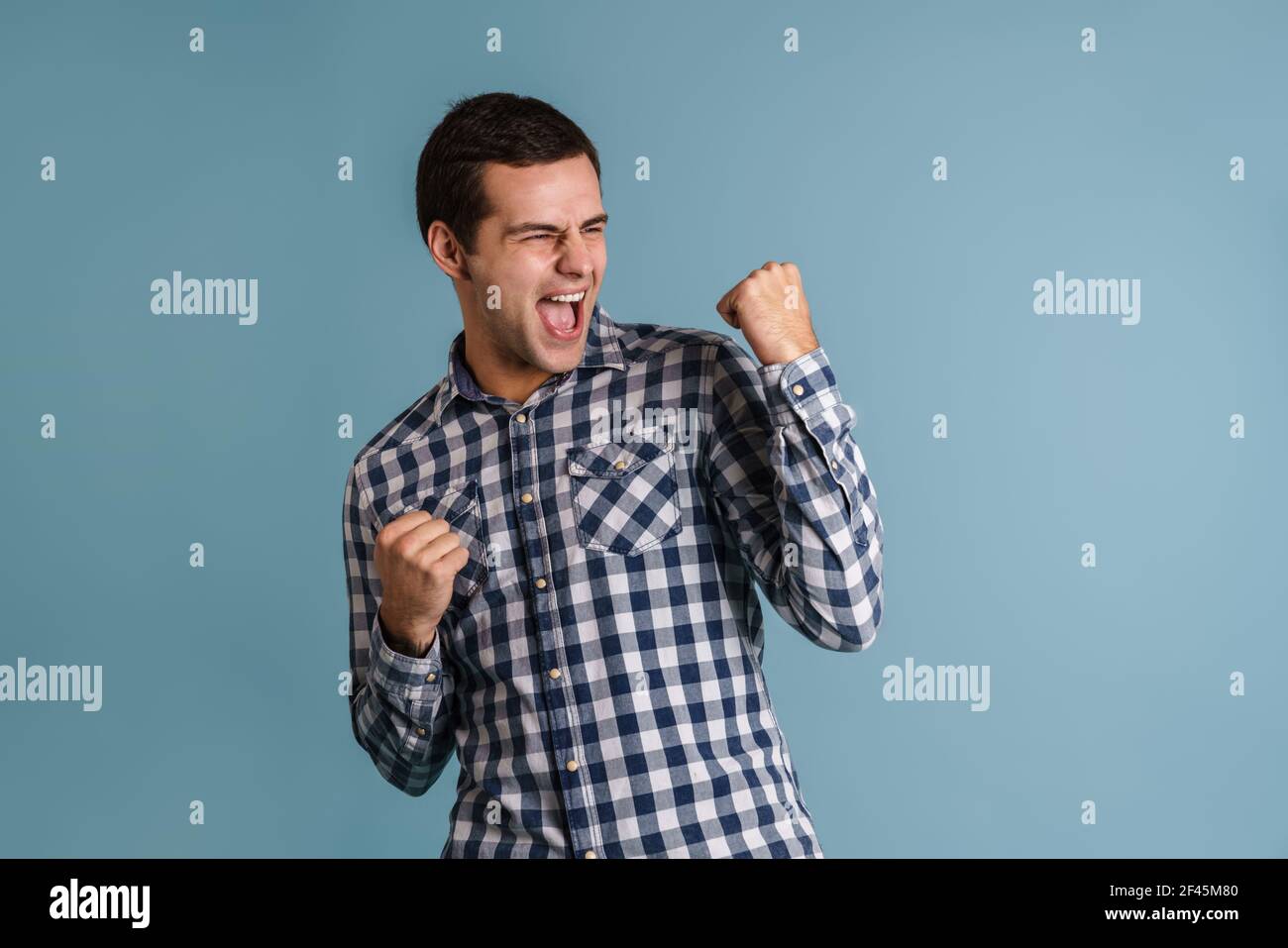Excited young guy screaming while making winner gesture isolated over ...
