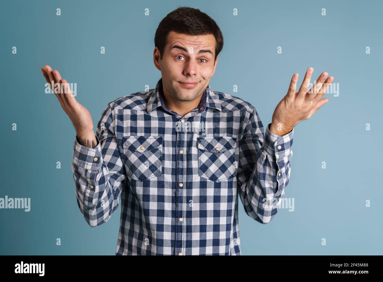Confused young casual man gesturing isolated over blue background Stock ...