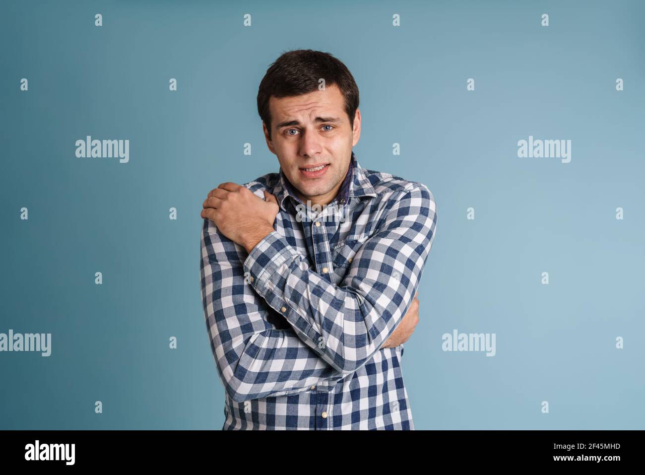 Portrait of handsome sick cold man standing isolated on blue background ...