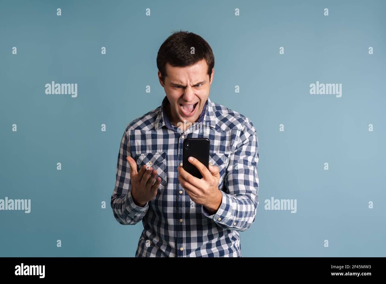 Portrait of an angry unsatisfied man using mobile phone and yelling ...