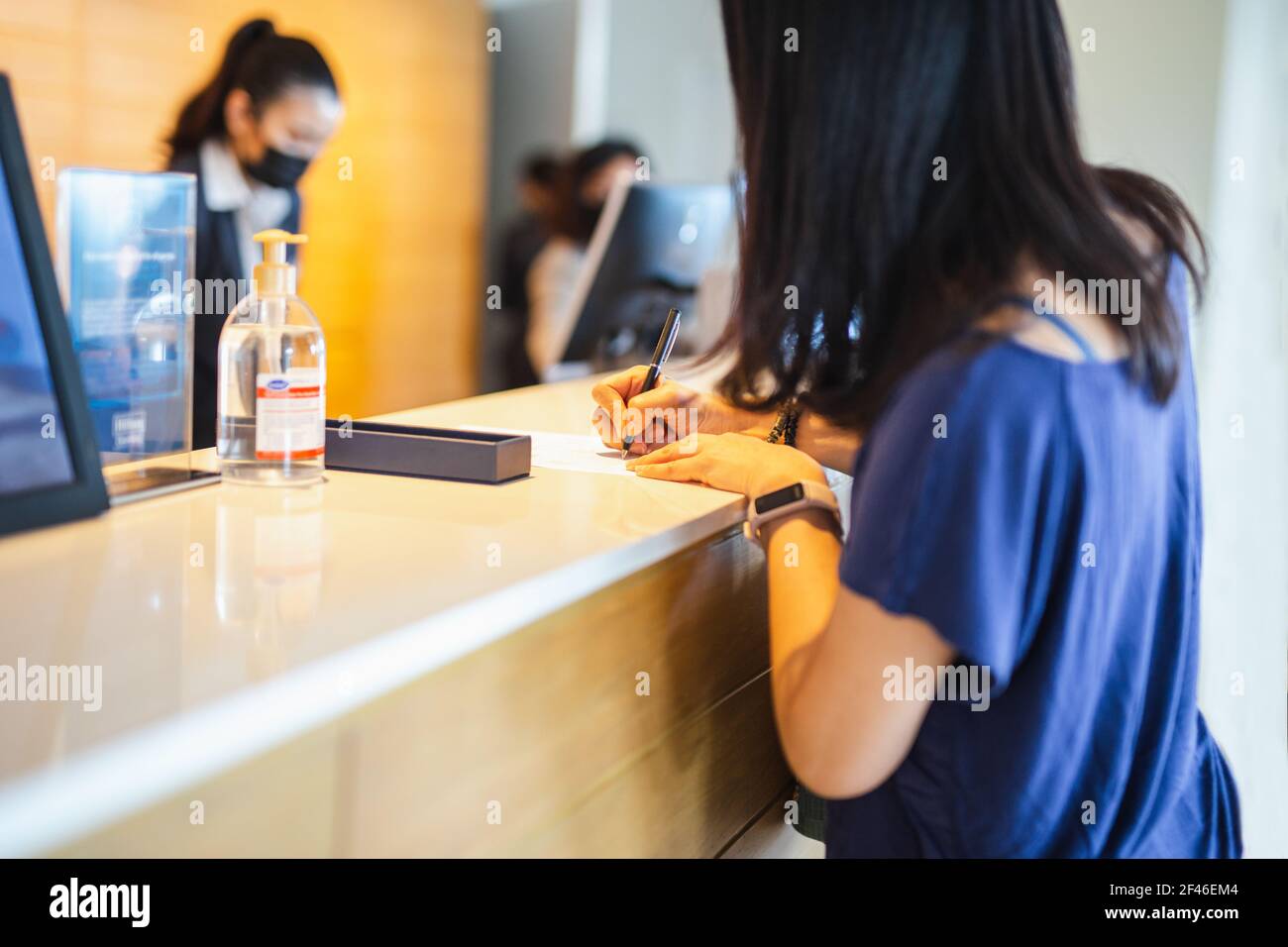 Woman guest signing bill at hotel reception Stock Photo - Alamy