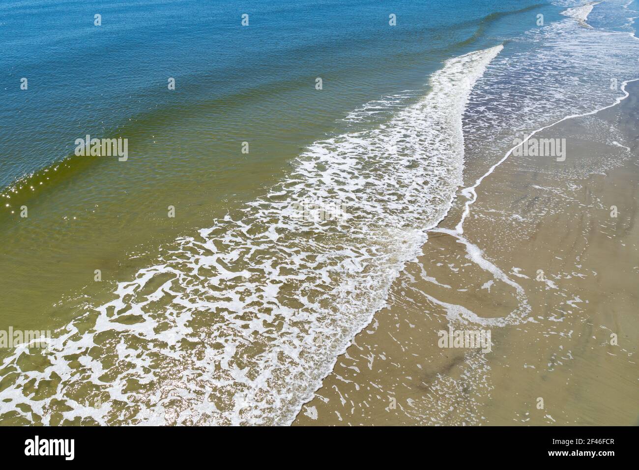Low waves of crystal blue and green ocean waters at shoreline, seafoam ...