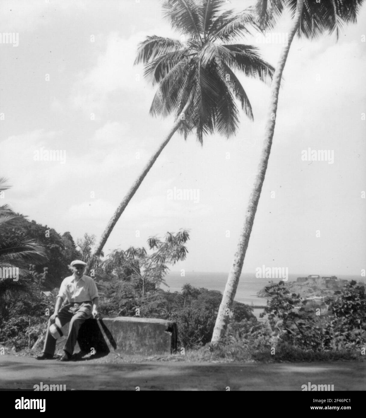 Travel photos Grenada. Tourist, sitting on a stone block under a palm ...
