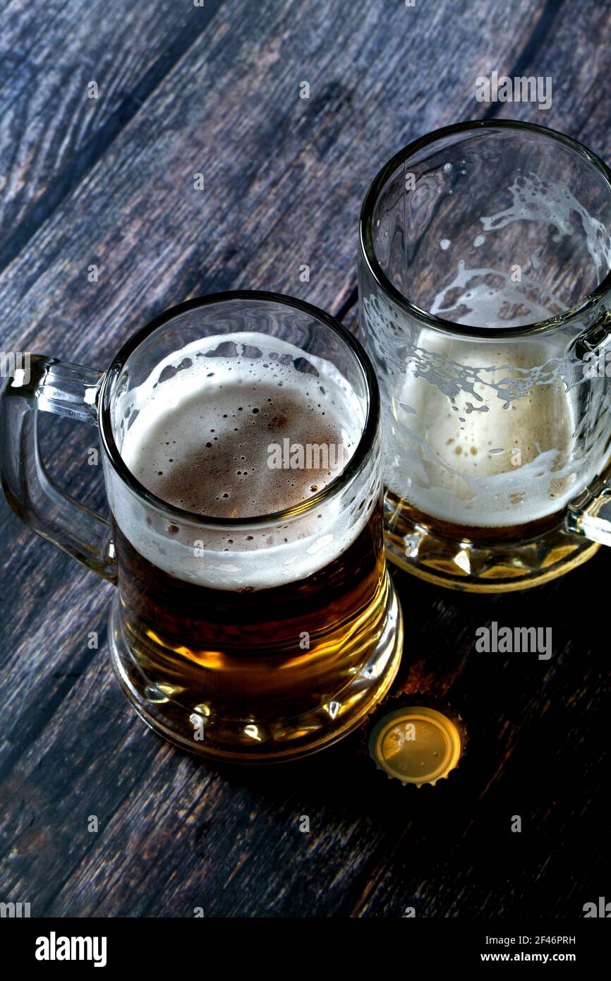 A vertical shot of two mugs of beer on wooden table Stock Photo - Alamy