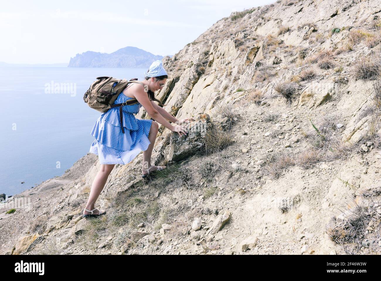The girl traveler climbs the mountain to the top. Woman with a backpack ...