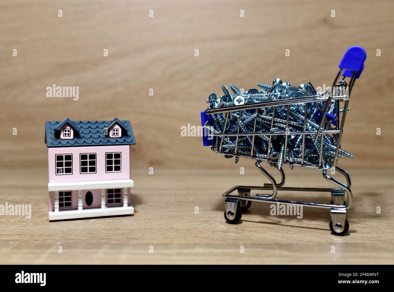 Self-tapping screws in a shopping cart and house on wood background ...