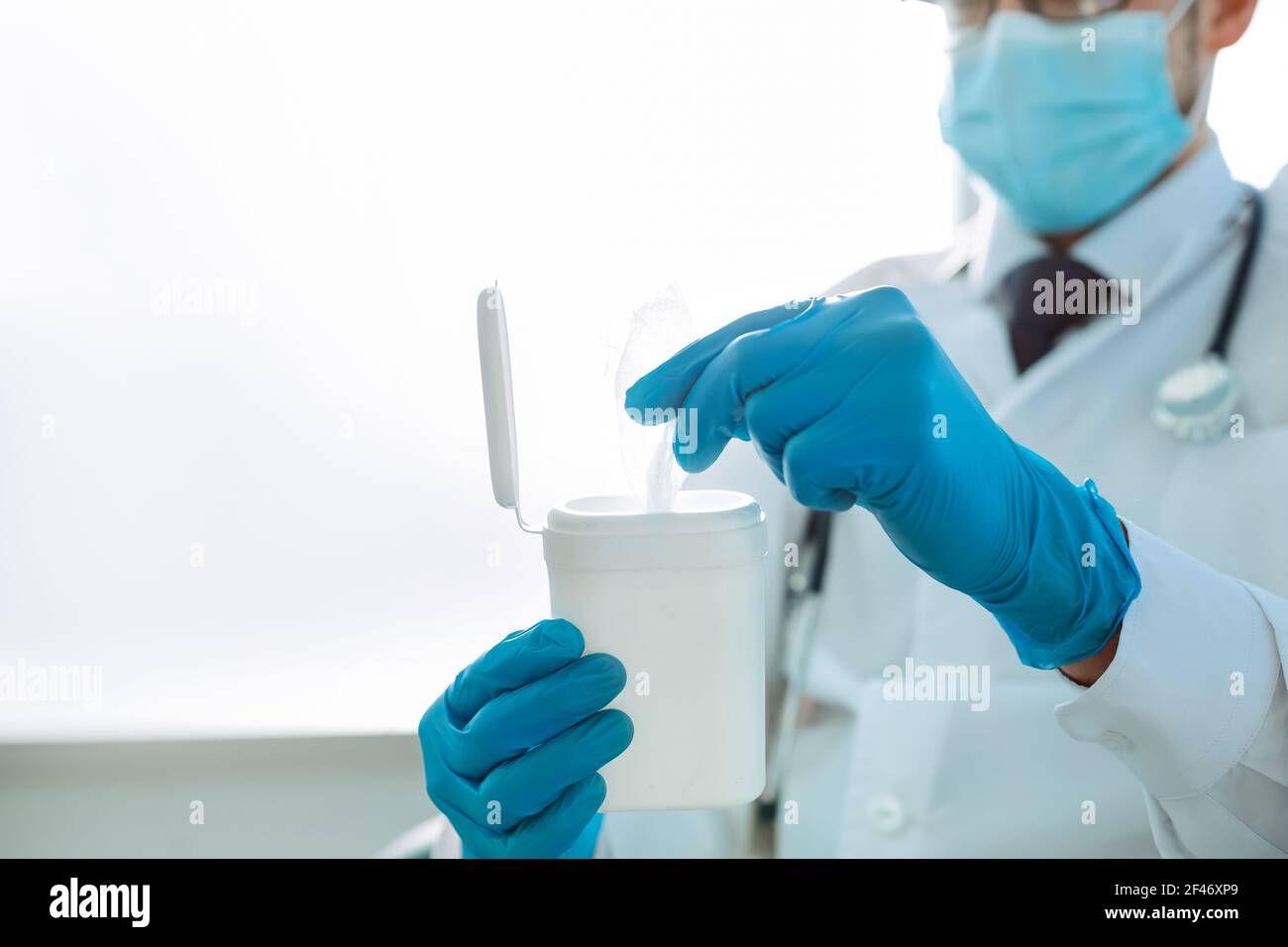 doctor in protective gloves takes out a wet wipe from the container ...