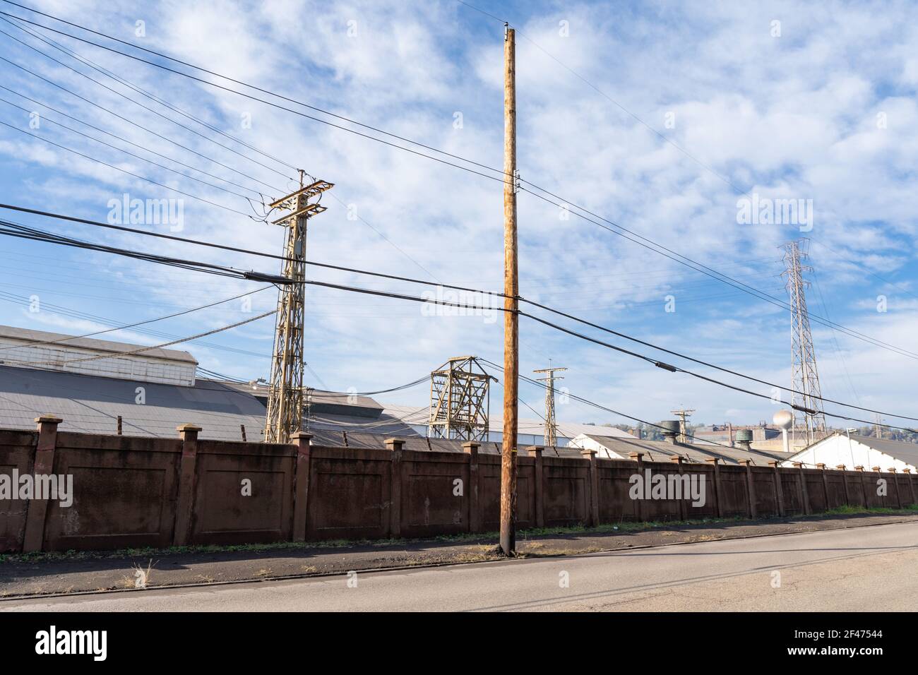 Long wall between street and industrial steel mill, power lines, blue ...