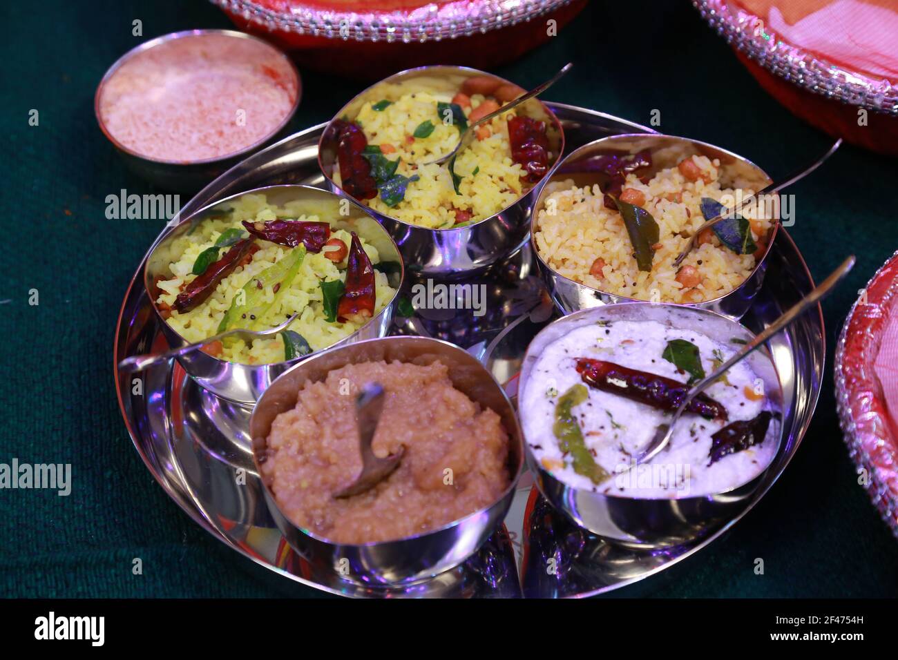 A closeup shot of Indian traditional dishes in small bowls with spoons ...