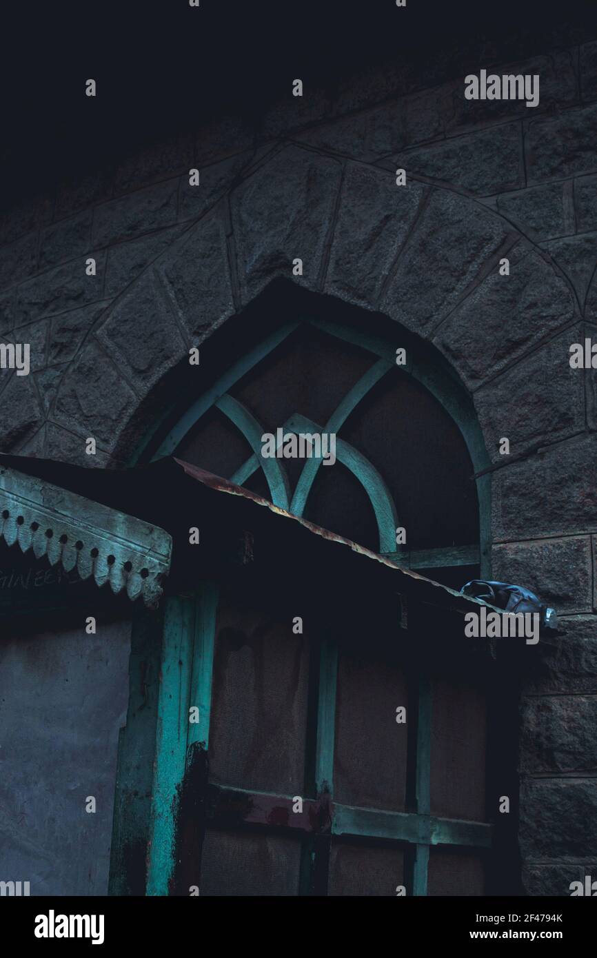 A vertical shot of a creepy dark window of the old-fashioned building ...