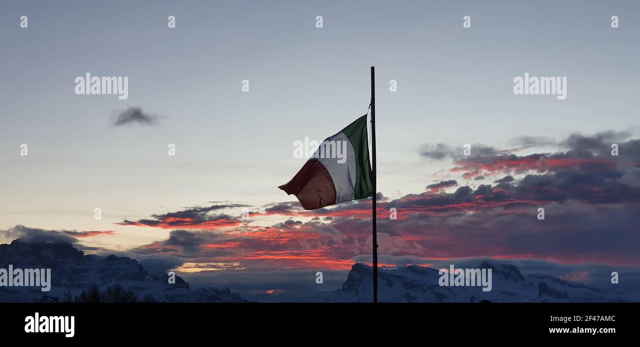 the Italian flag flutters as the sun sets with colored clouds Stock ...