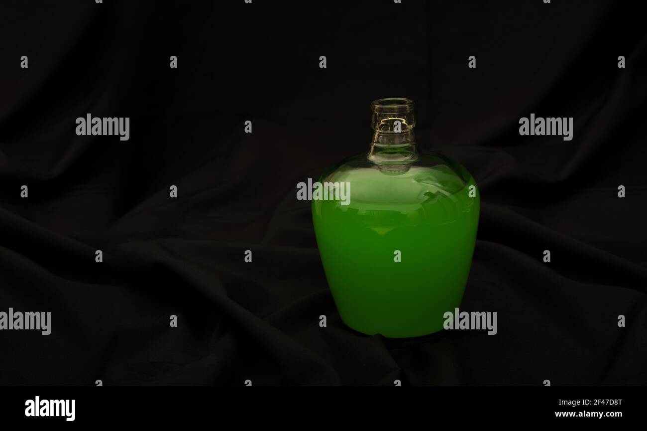 A closeup of bright neon green liquid in a simple perfume bottle ...