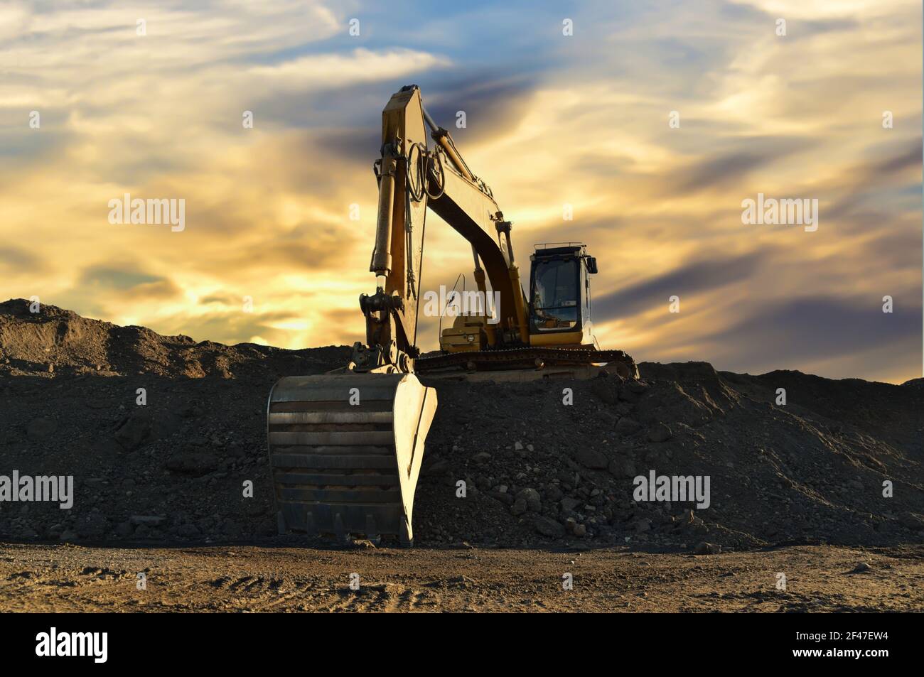 Excavator working on earthmoving at open pit mining on amazing sunset ...