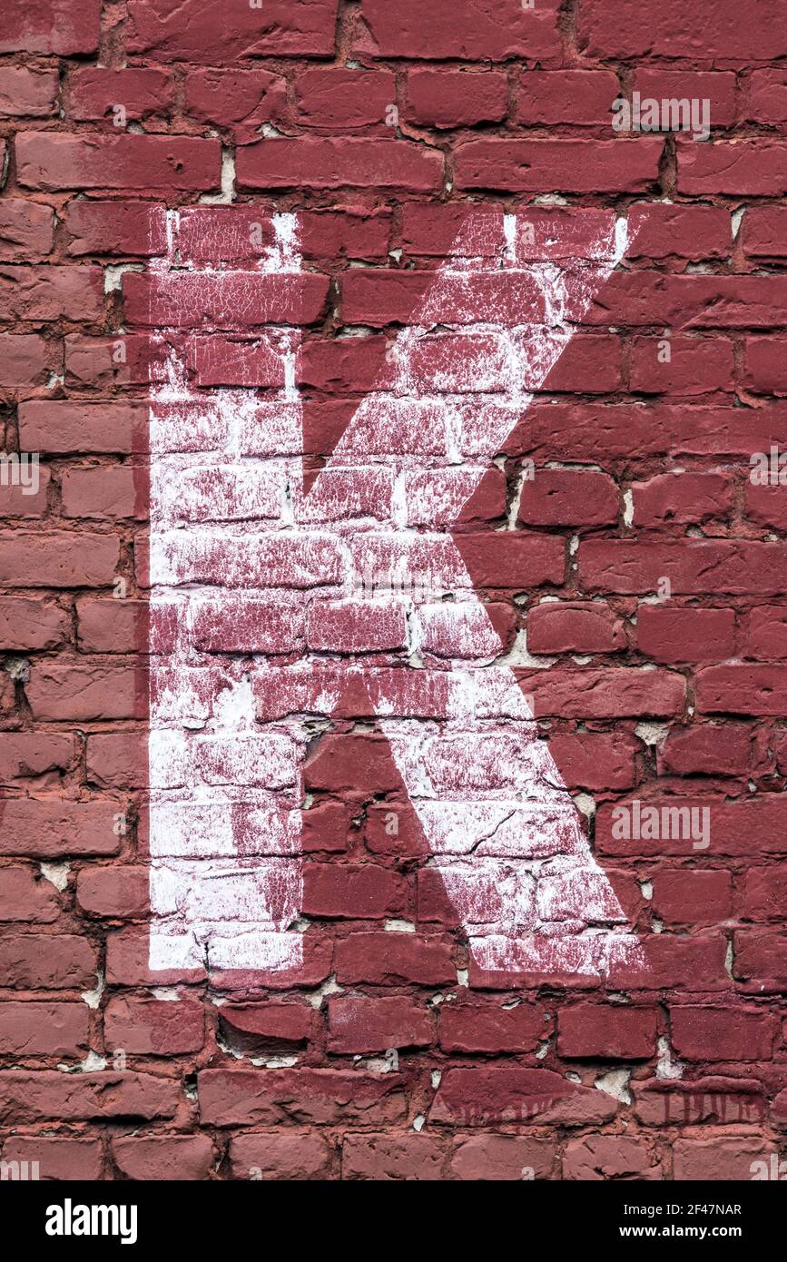 The letter K painted white on a red brick wall Stock Photo - Alamy