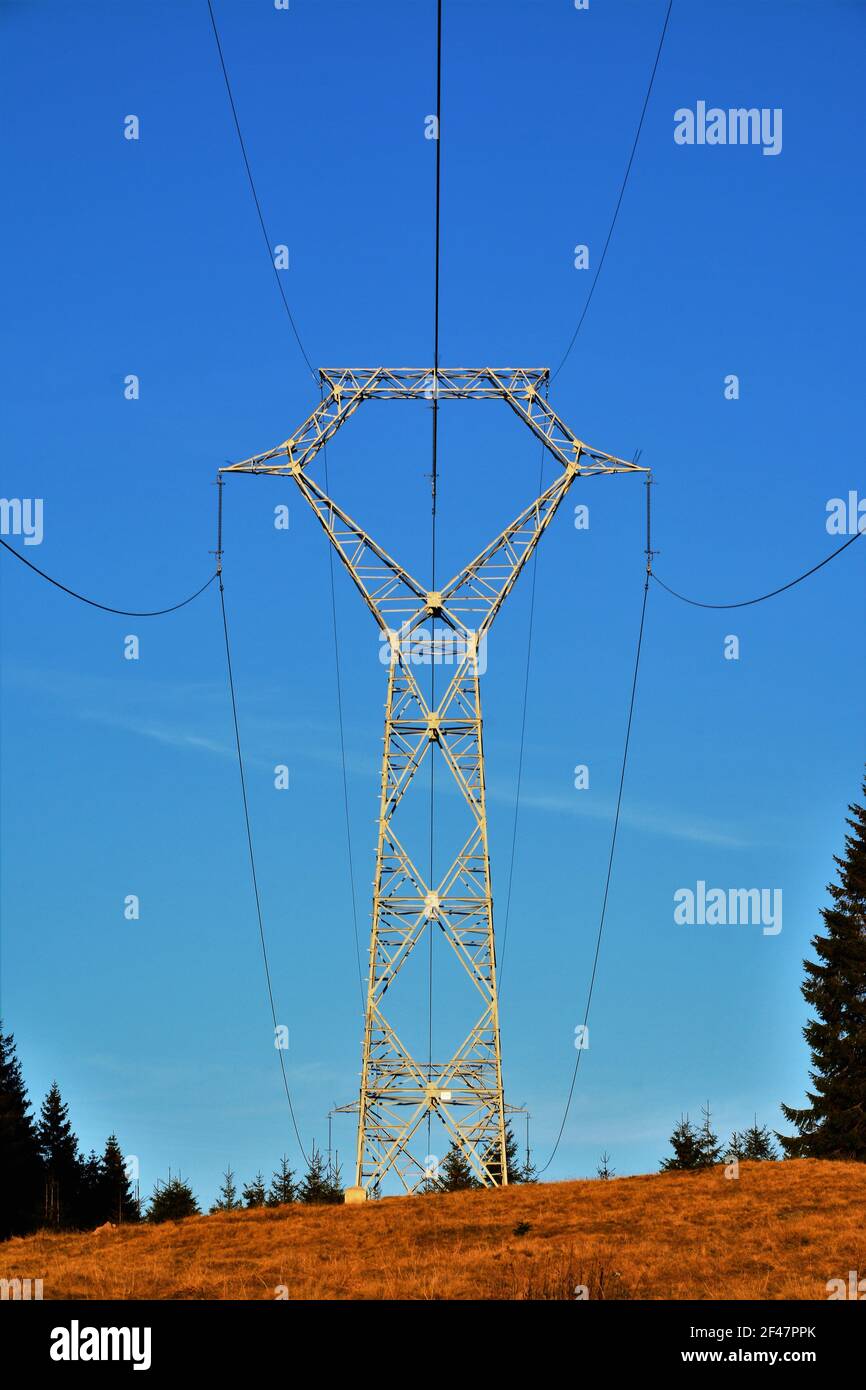 A vertical of an electricity pylon on the hill against the blue sky ...