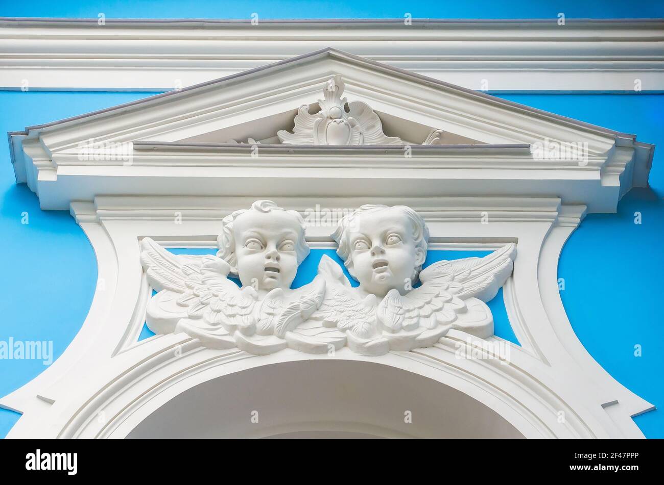 The faces of the angels above the stucco window on the church wall ...