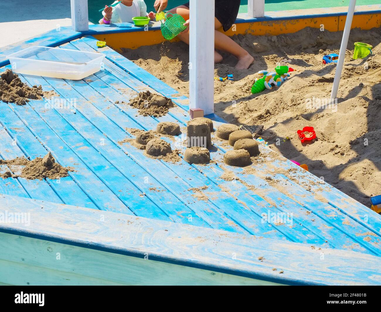 Blue wooden sandbox with sculpted sand cakes and many toys Stock Photo ...