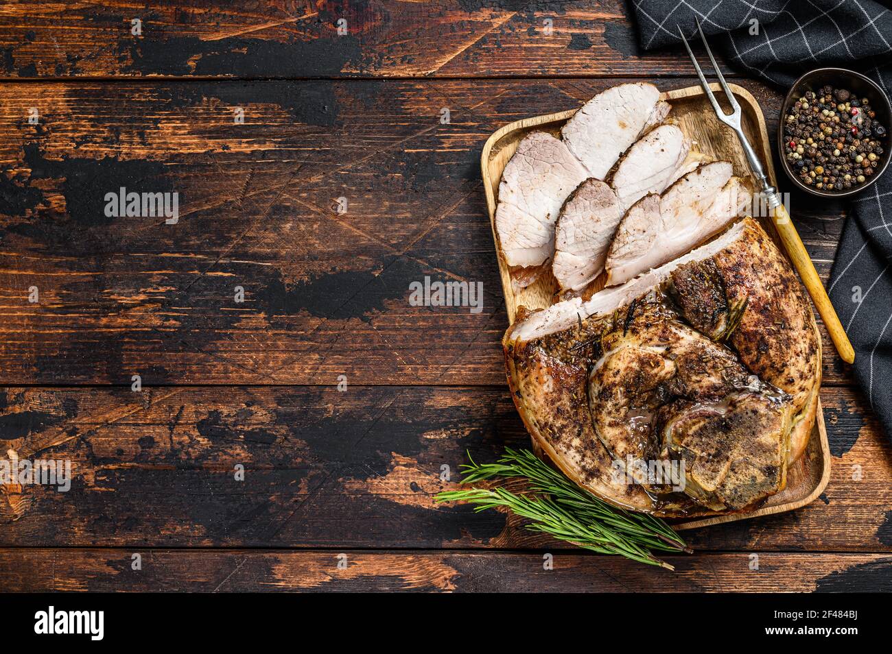 Baked sliced pork leg knuckle. Dark wooden background. Top view. Copy ...