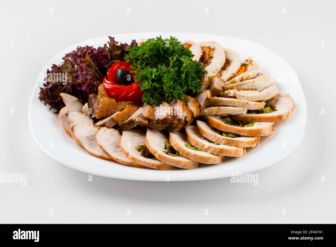 Isolated sliced chicken roll platter with greens Stock Photo - Alamy