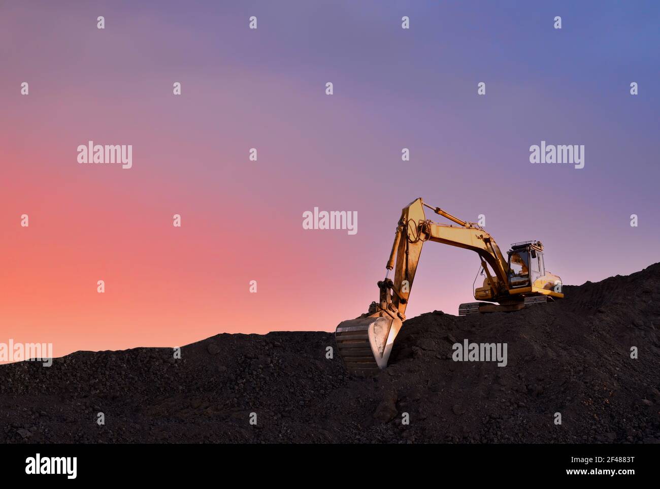 Excavator working on earthmoving at open pit mining on sunset ...