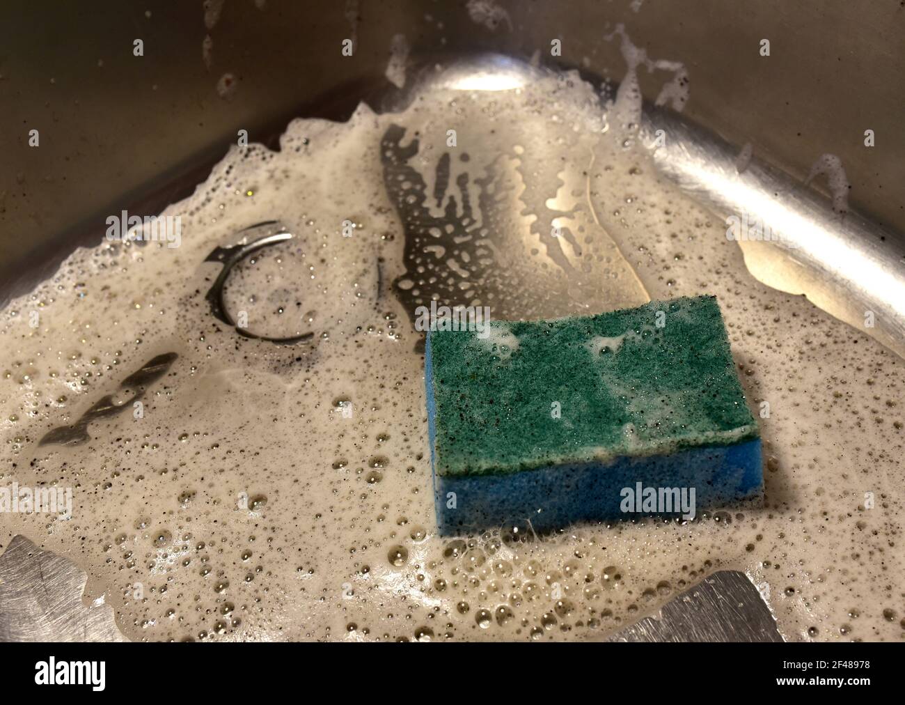 Sponge with detergent and foam while washing the sink in the kitchen ...
