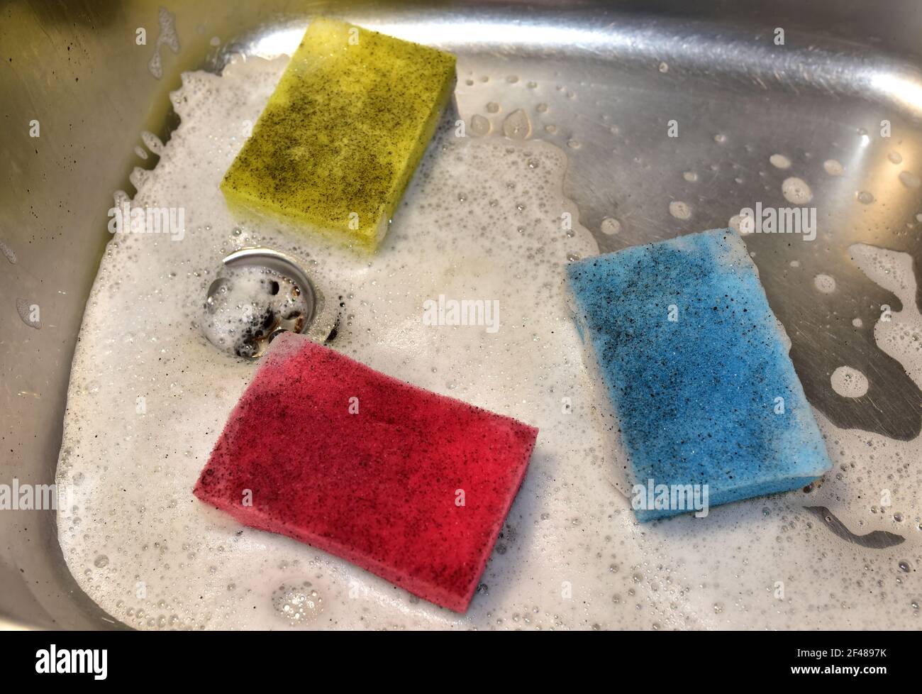 Sponge with detergent and foam while washing the sink in the kitchen ...