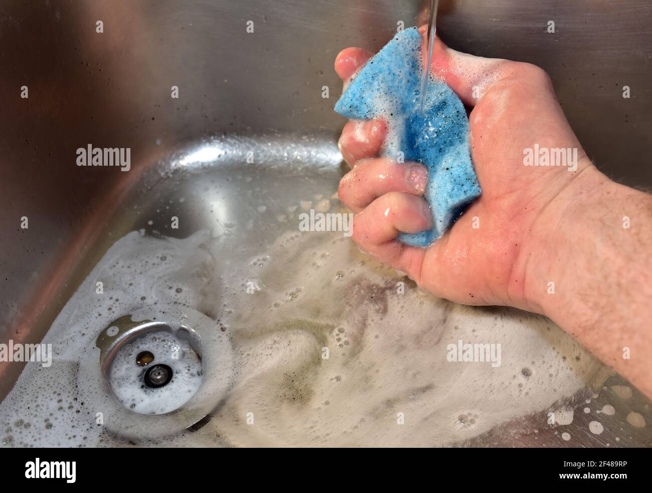Sponge in hand with detergent and foam while washing sink in the ...