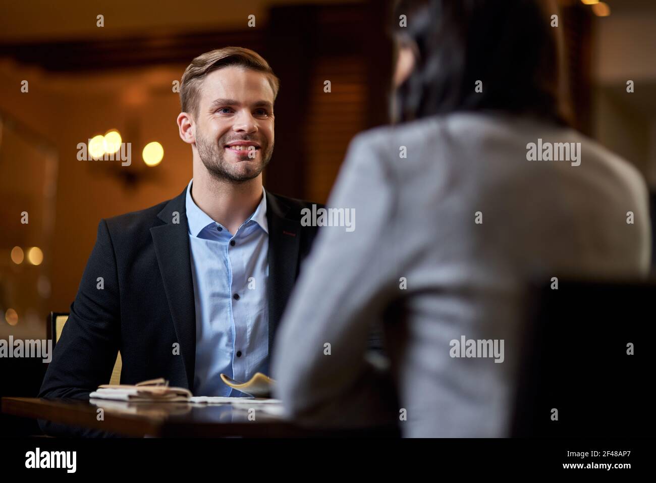 Gladsome gentleman sitting across table from a lovely lady Stock Photo ...