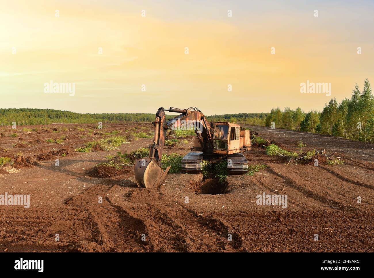 Excavator digging drainage ditch in peat extraction site. Drainage of ...