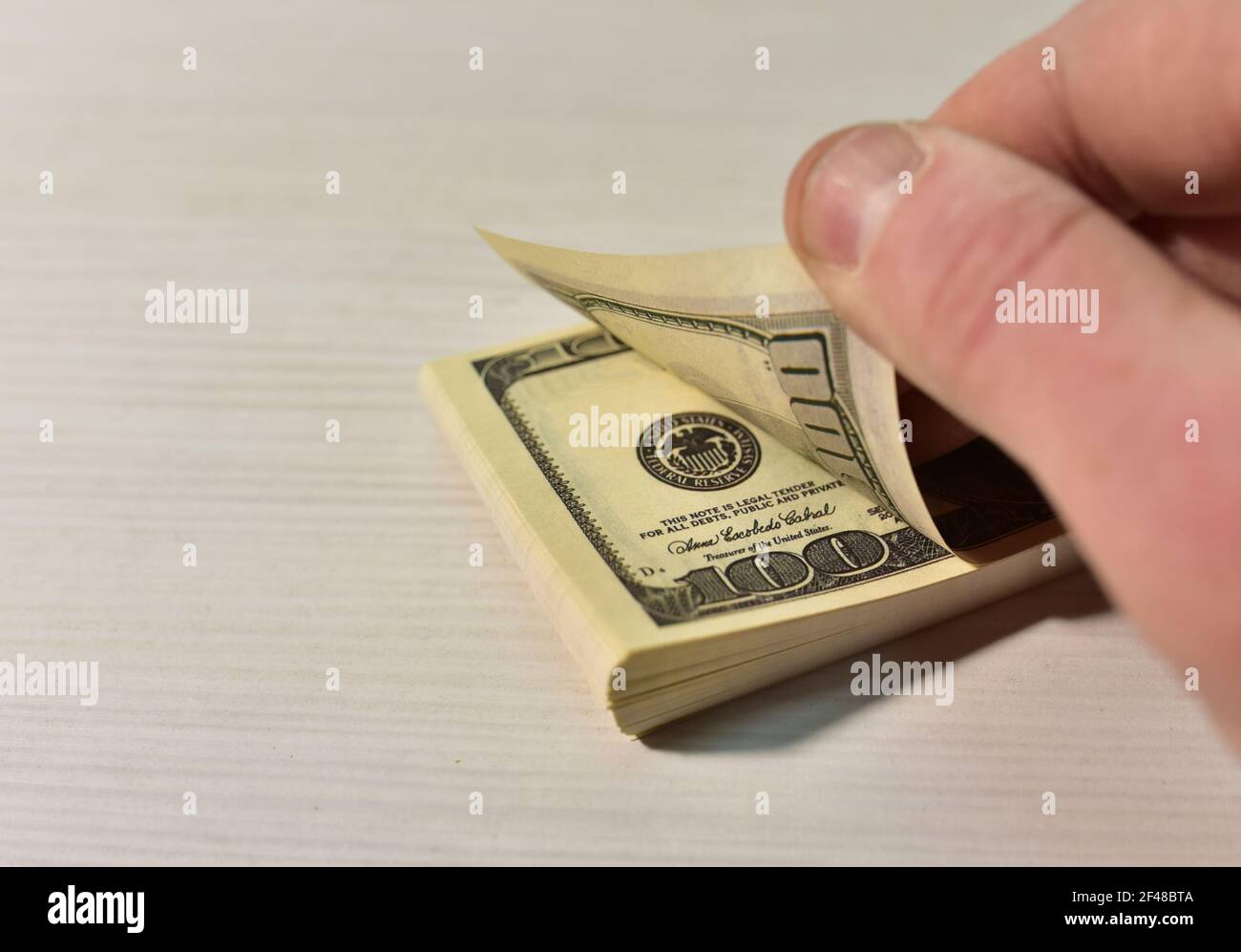 A bundle of one hundred dollar bills during counting. Money account concept. Man's hand counts ...
