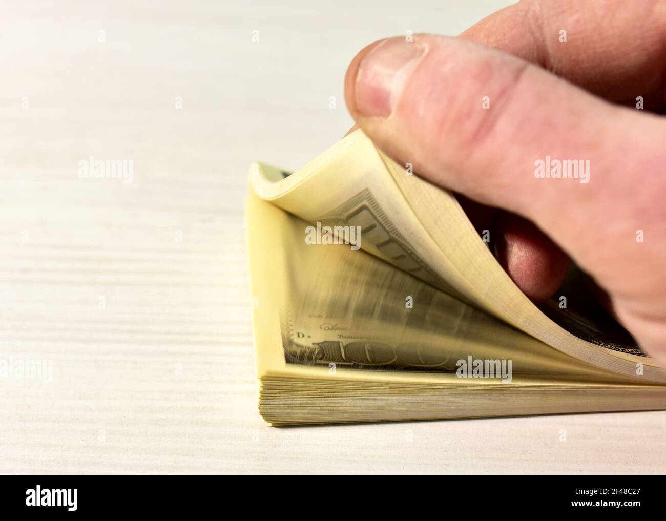 A bundle of one hundred dollar bills during counting. Money account concept. Man's hand counts ...