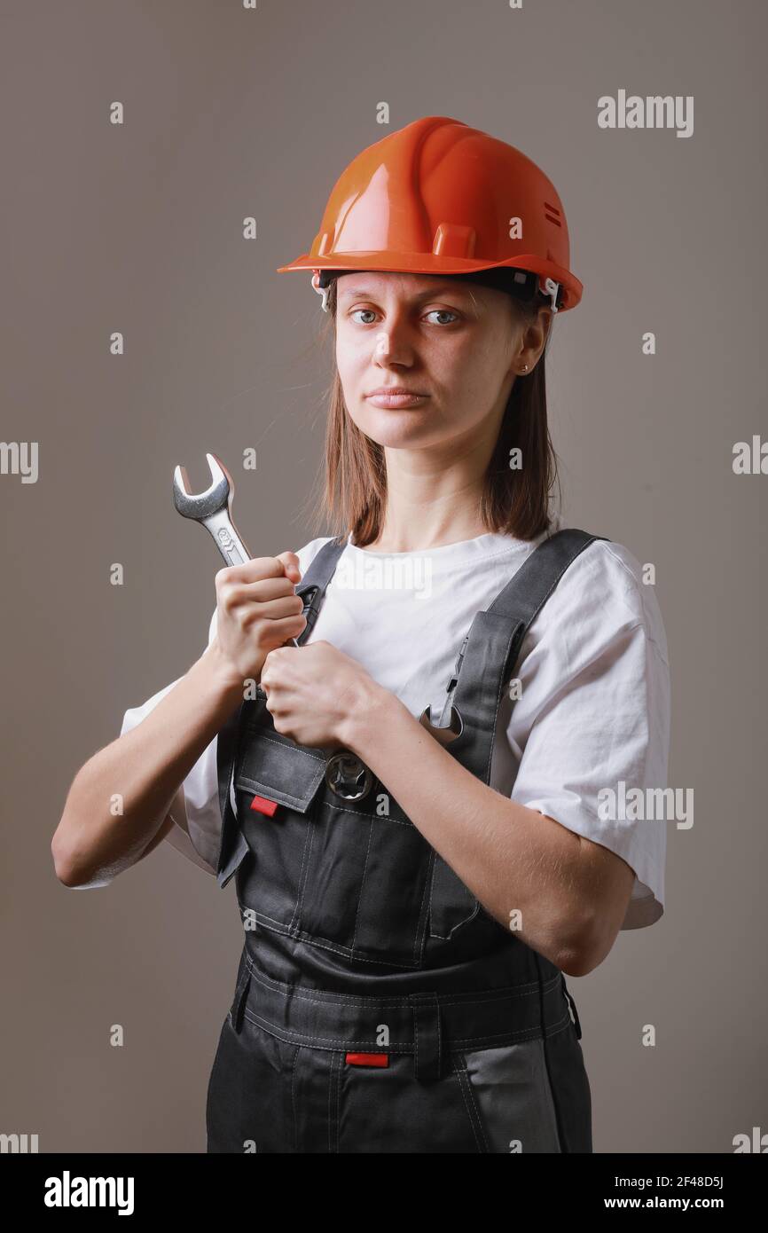Young beautiful female engineer worker in a gray uniform and safety ...