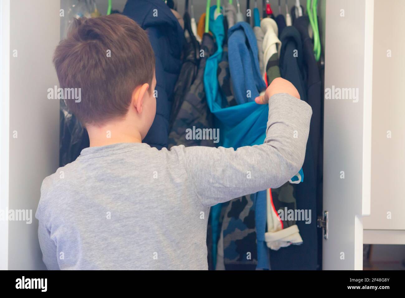 Baby Choosing Clothes in Wardrobe at Home Stock Photo - Alamy