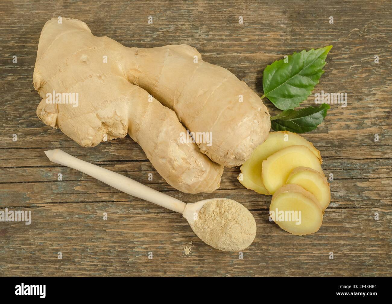 Ginger root with chopped wedges and dry powder on wooden background ...