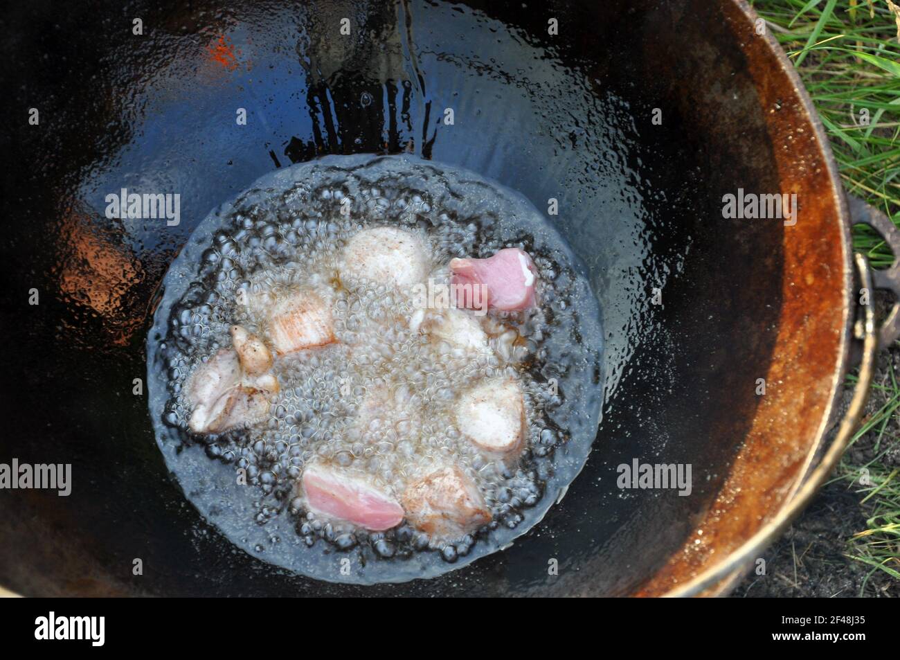Frying meat in outdoor cauldron on fire. Traveling, tourism, picnic ...